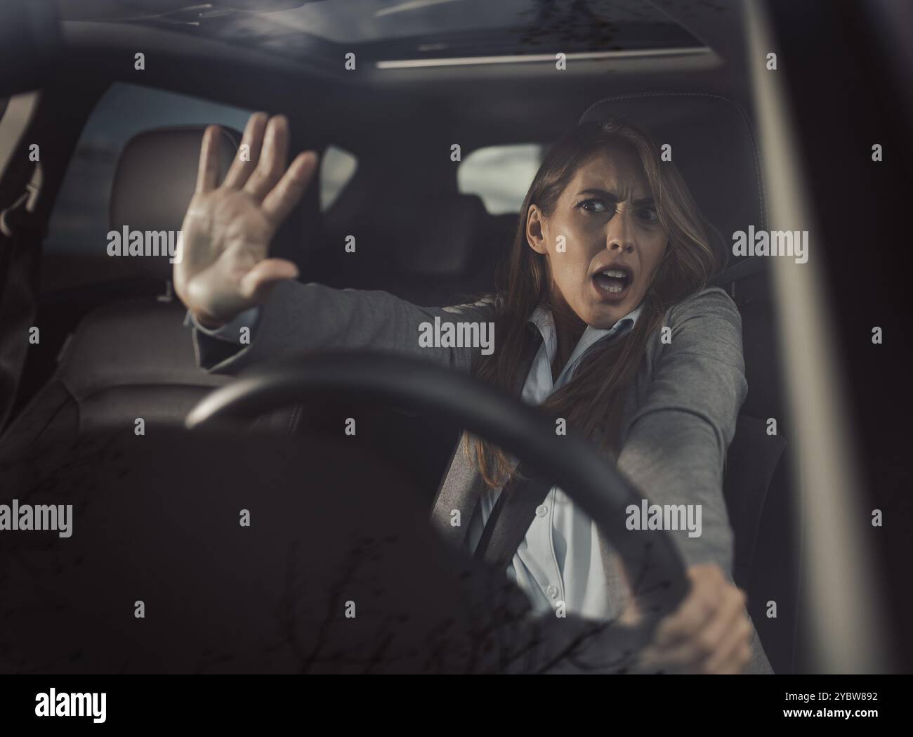 Pretty young woman driving car and having afraid and shocked face ...