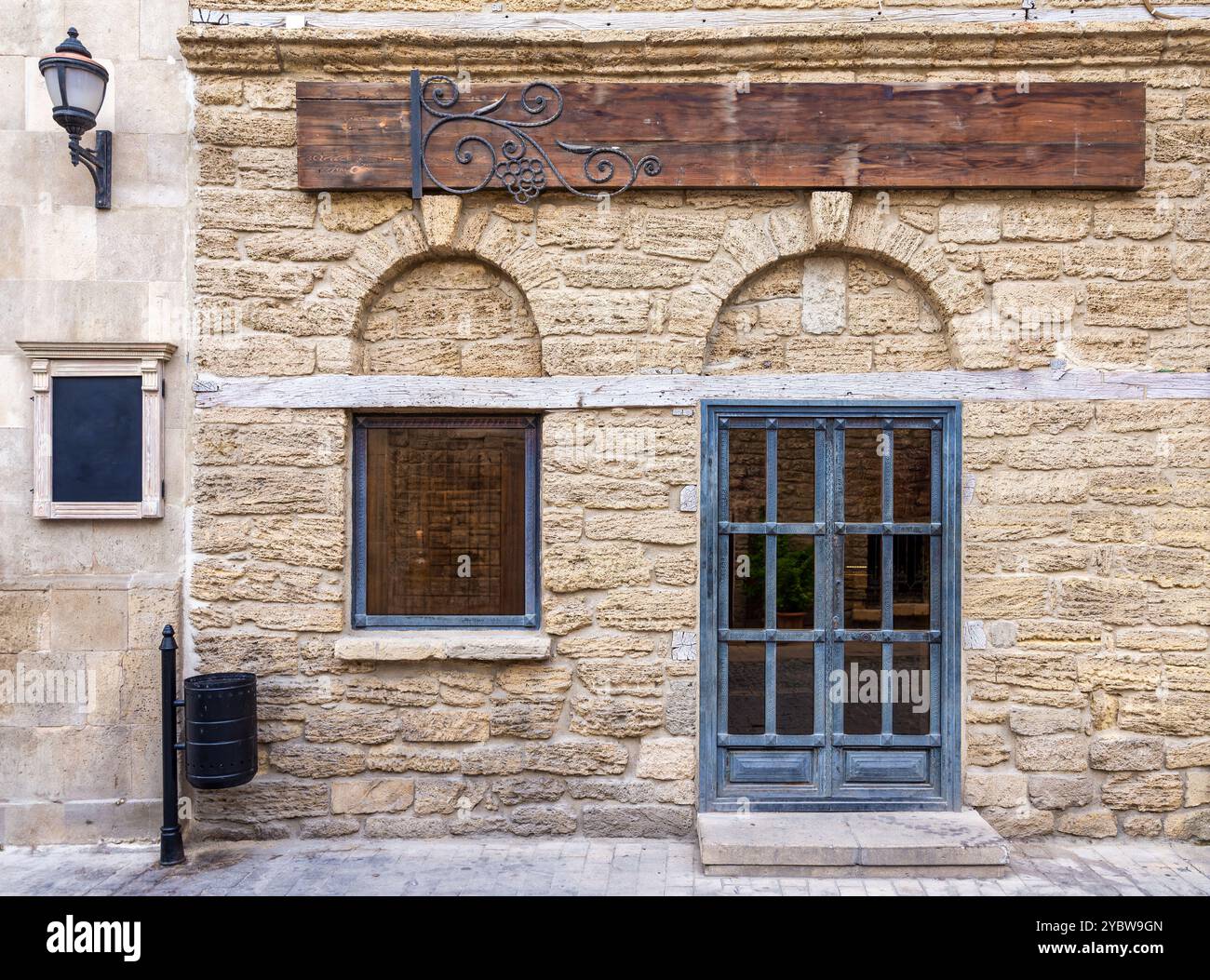 An entrance to a rustic stone building features a wooden sign above and ...