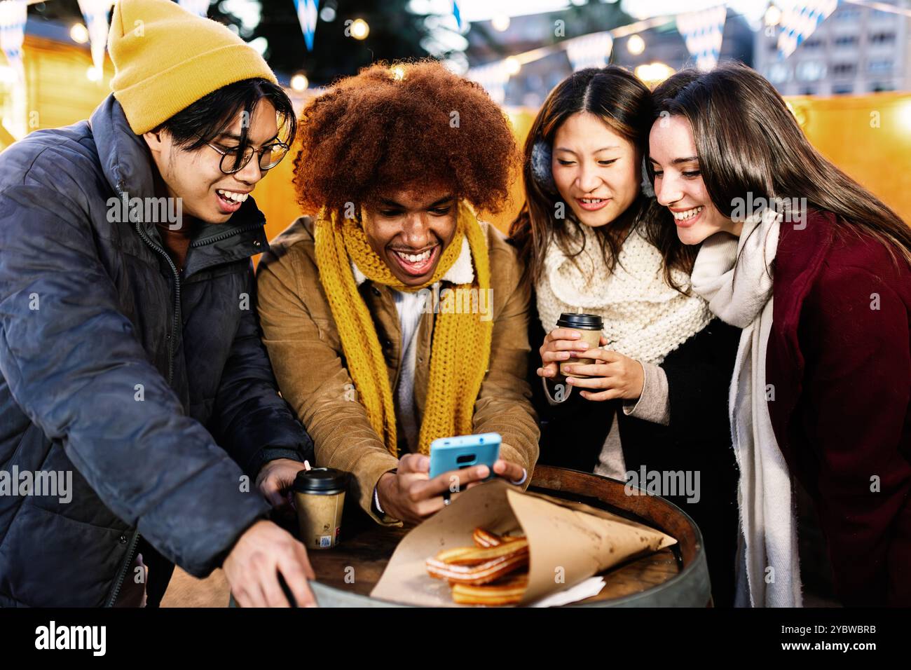 Young multiracial group of friends in winter clothes using mobile phone ...