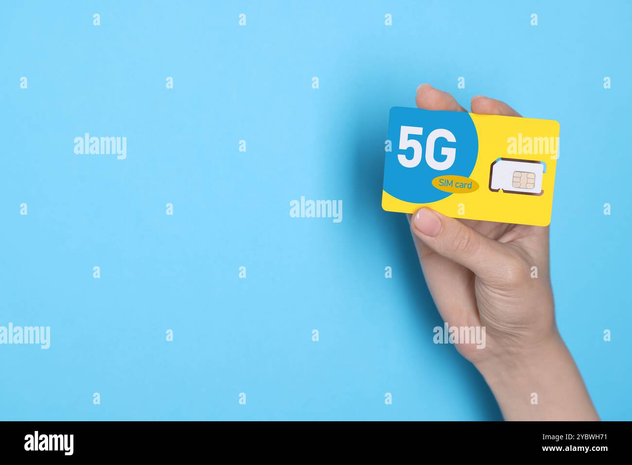 Woman holding 5G SIM card on light blue background, closeup. Space for ...