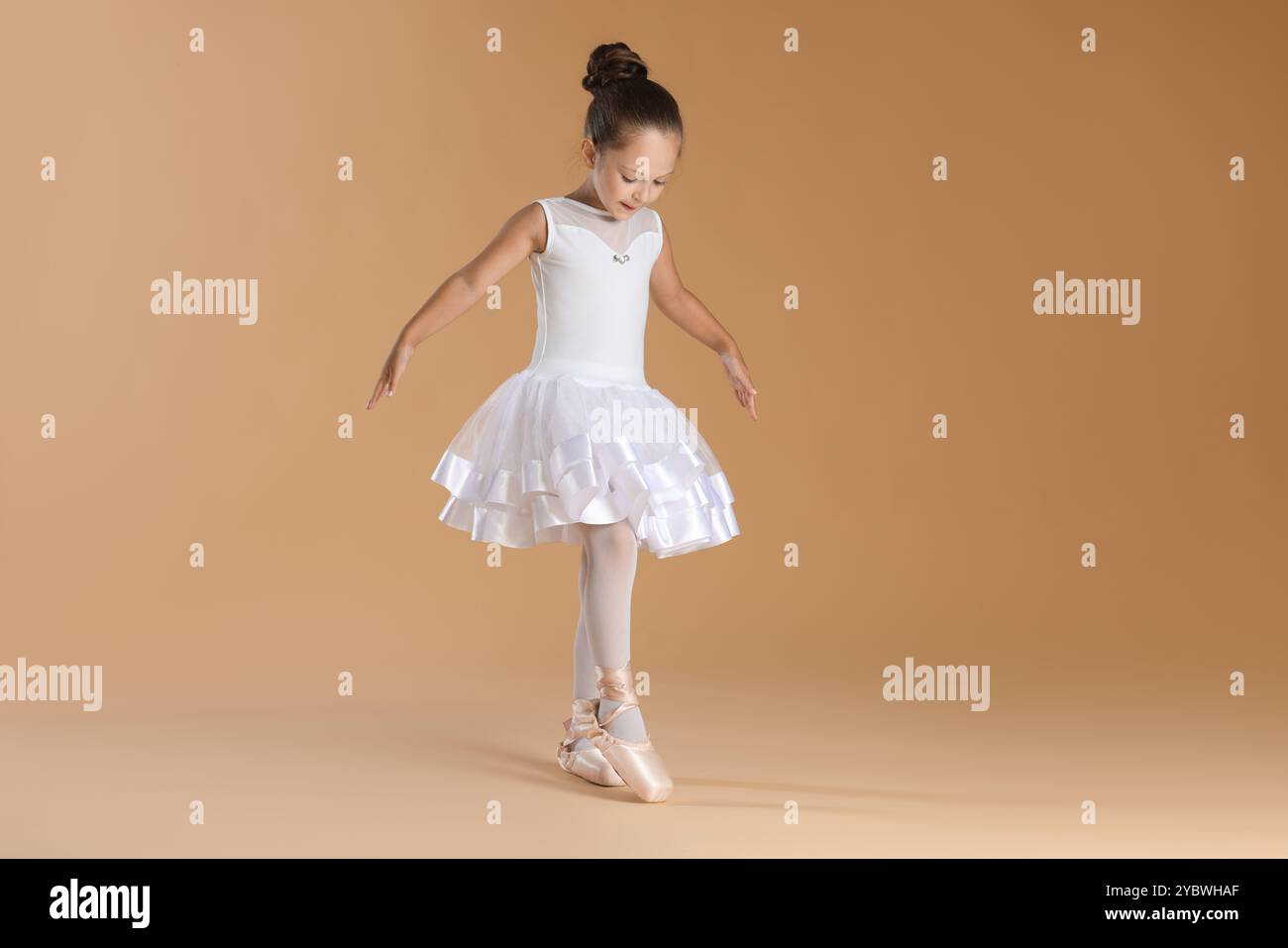 Little ballerina practicing dance moves on beige background Stock Photo ...