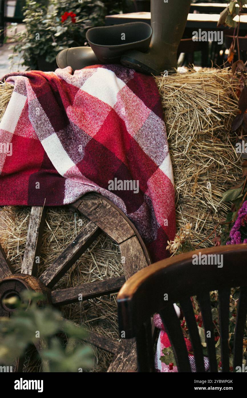 Red and white checkered plaid on hay with rubber boots wooden wheel ...
