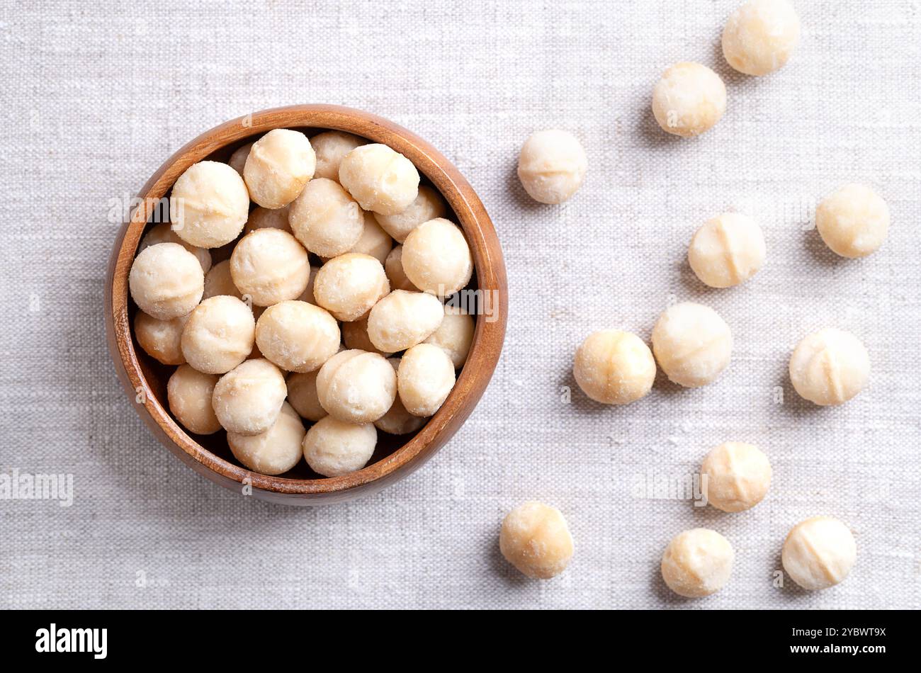 Macadamia nuts, roasted and salted, in a wooden bowl on linen fabric ...
