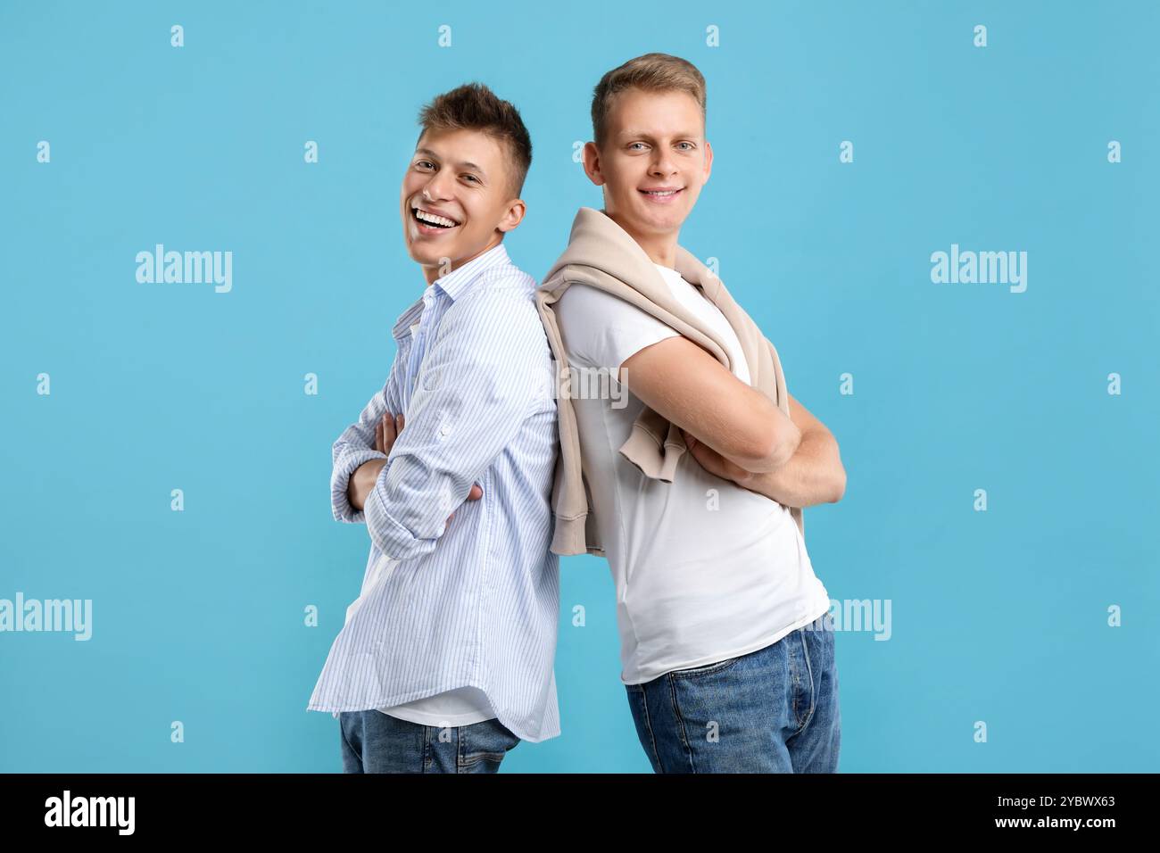 Happy brothers posing with crossed arms on light blue background Stock ...