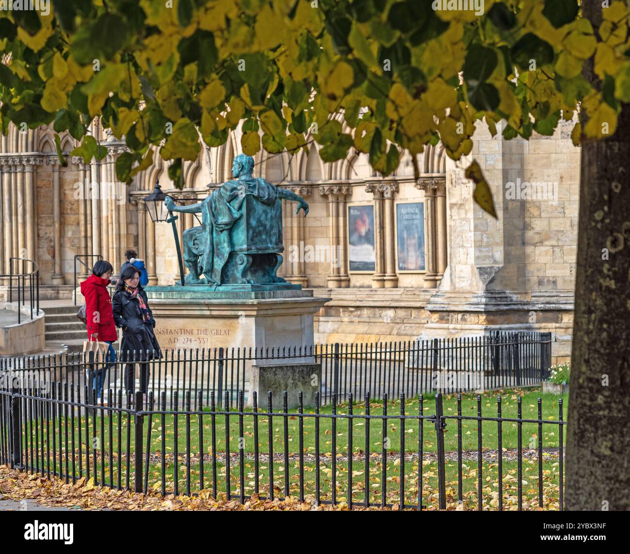 Two tourists stand reading an inscription on a stone slab. A statue of ...