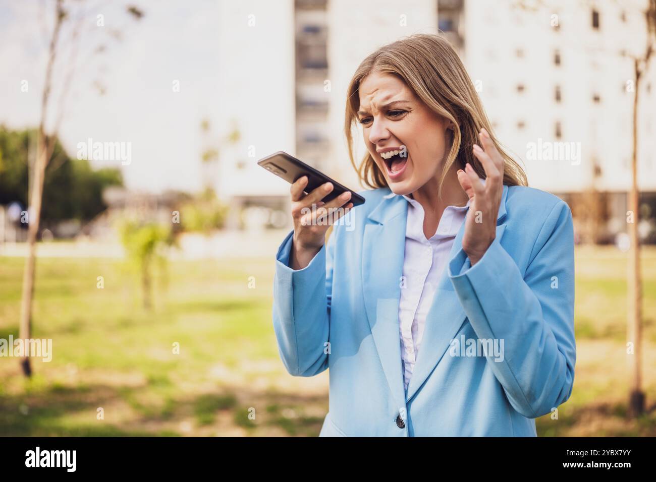 Image of angry businesswoman screaming on the phone while standing ...