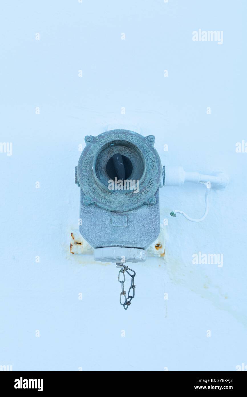 A grey switch on a ship's white wall, corroded by salt air, captures ...