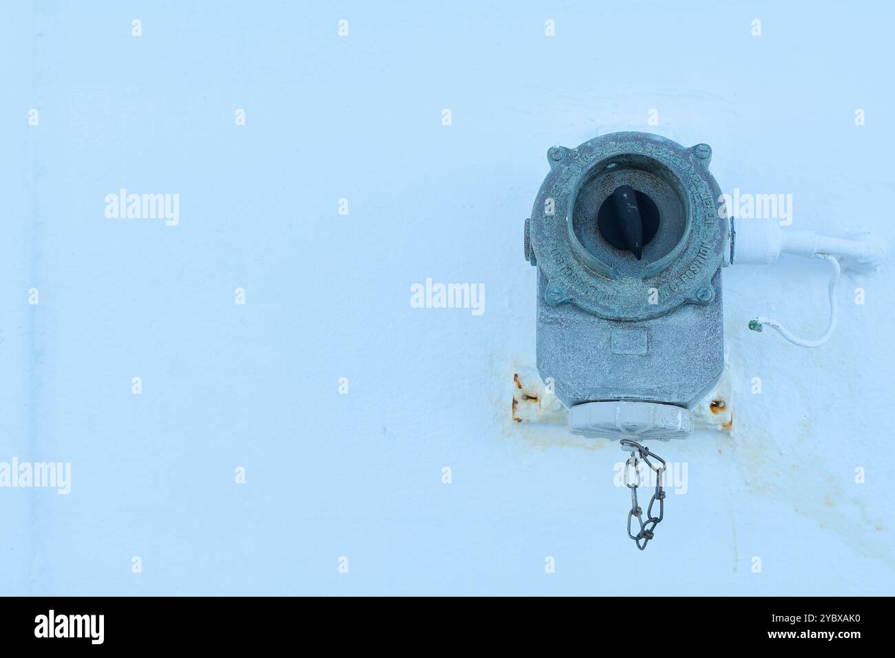 This image shows a weathered switch on a white wall of a ship, clearly ...
