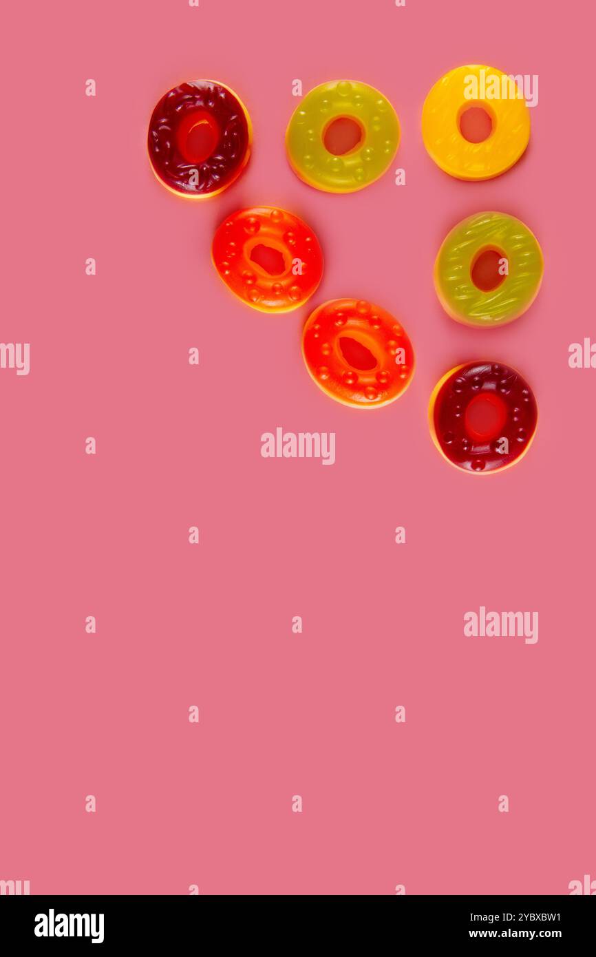 Triangle of round jelly candies at the corner of pink background ...