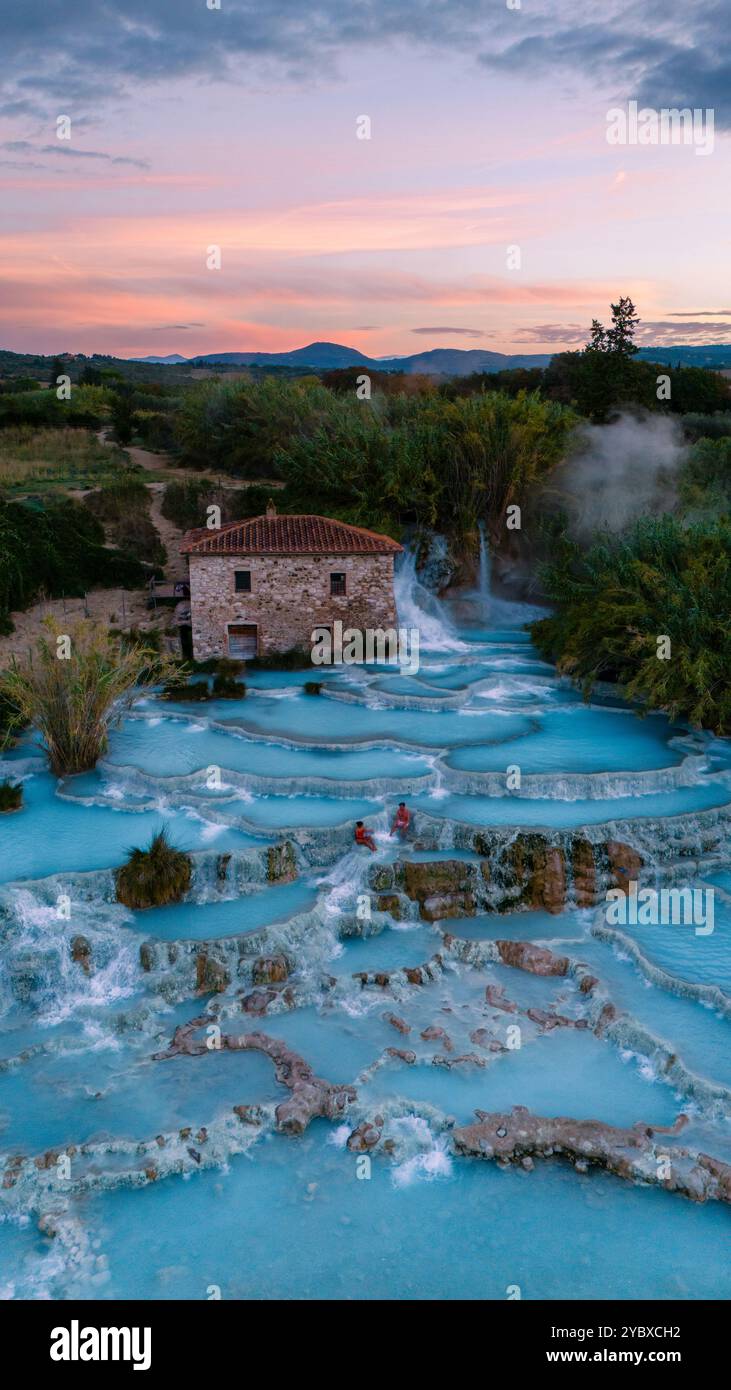 Visitors soak in the warm thermal springs of Saturnia as the sun sets ...