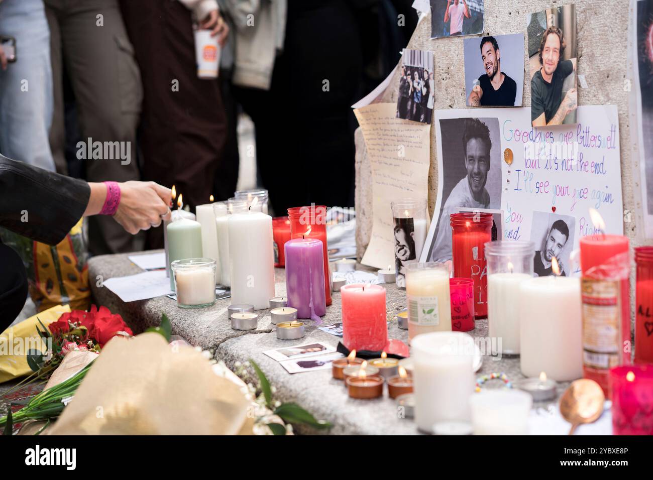A person lights a candle during a tribute in memory of singer Liam ...