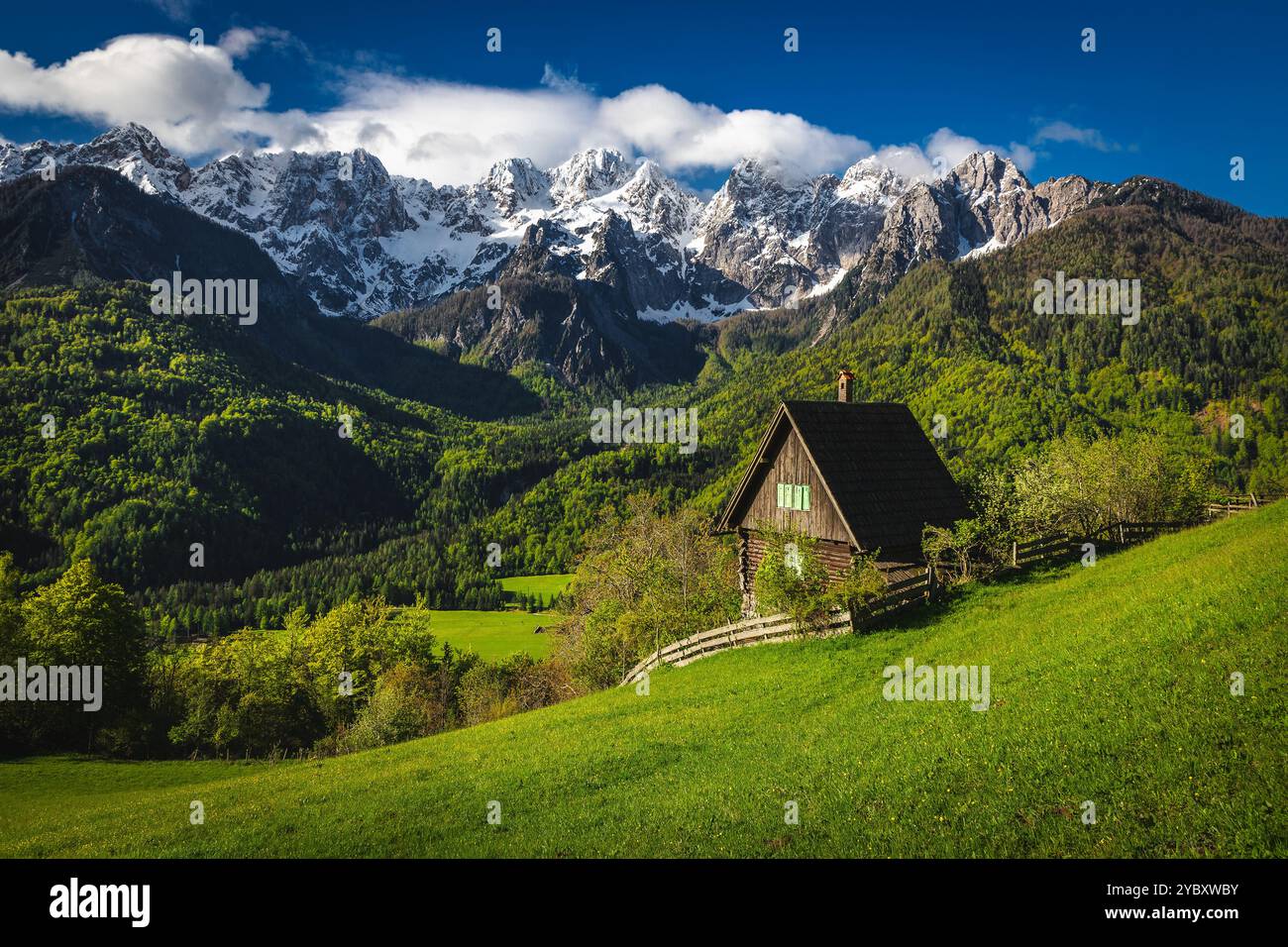 Stunning spring alpine scenery with fabulous wooden hut on the green ...