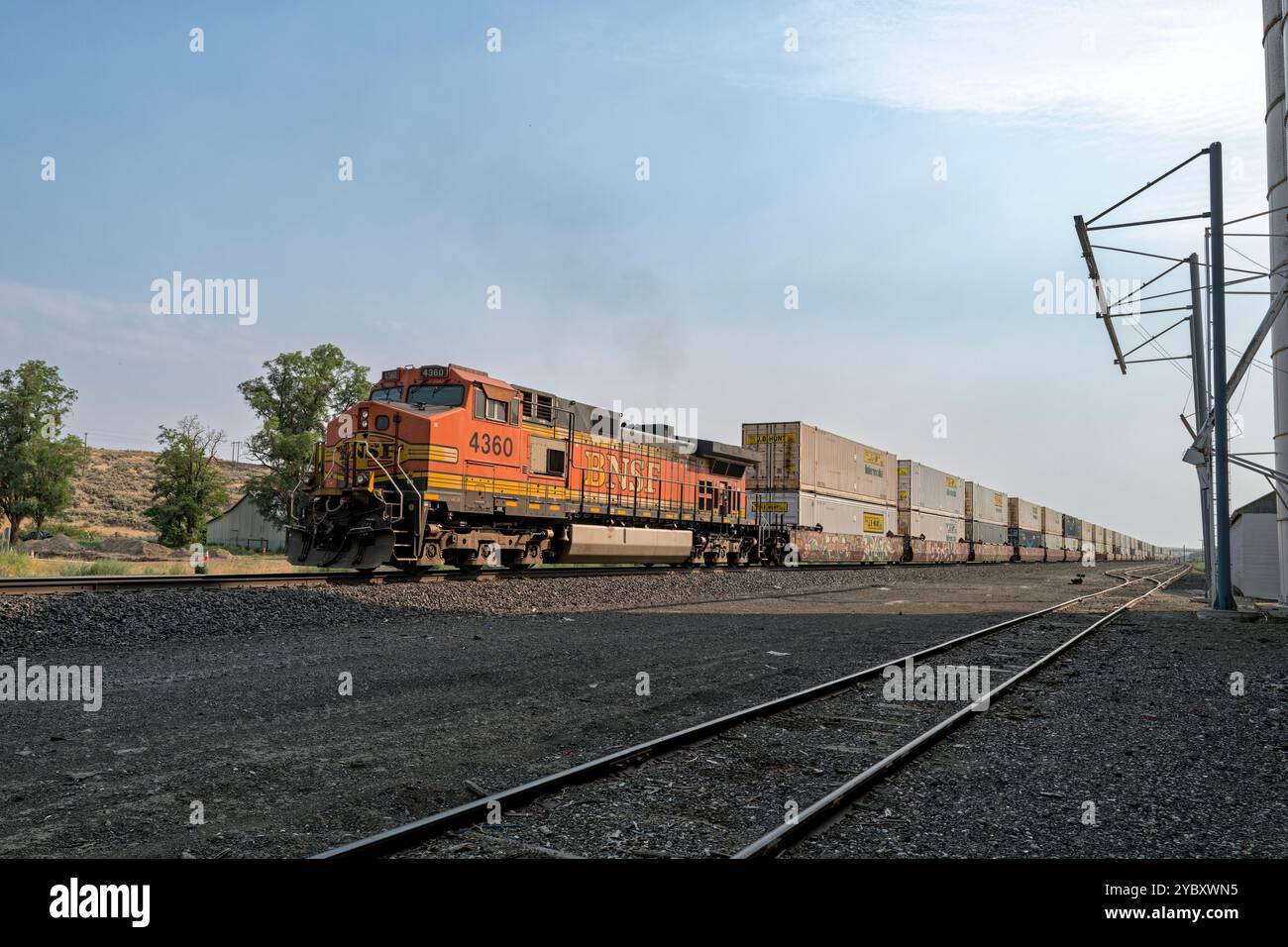 BNSF locomotive 4360 pushes a freight train past the grain elevator in Lamona, Washington, USA ...