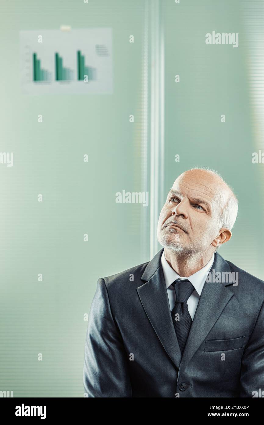 Businessman in a suit studies a sales chart, showing focus and ...