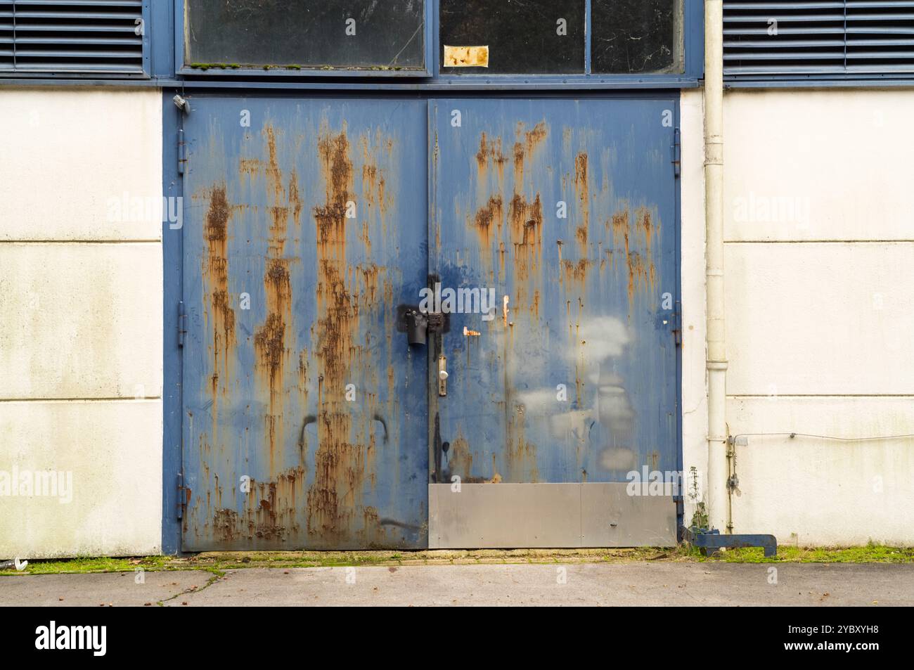 Old rusty blue metal door with damaged paint showing corrosion, an ...