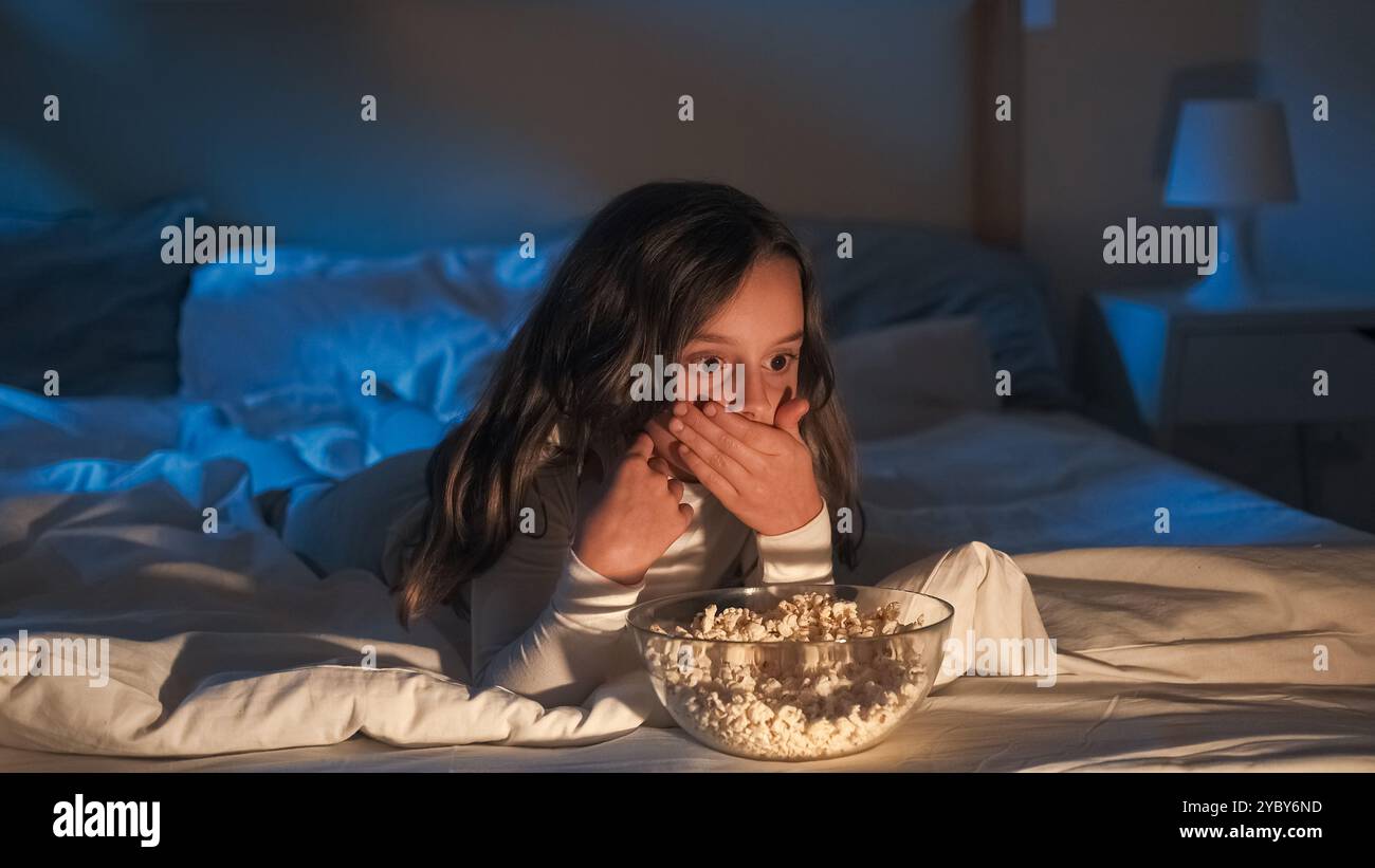 Bedtime movie. Late entertainment. Frightened scared shocked small girl ...