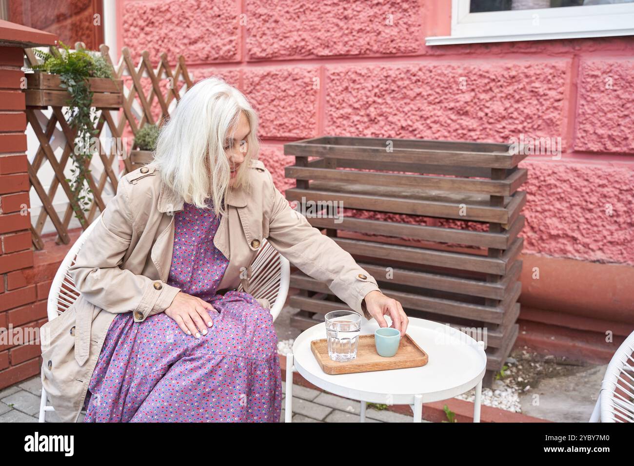 Senior woman enjoying a peaceful outdoor moment with coffee and water ...