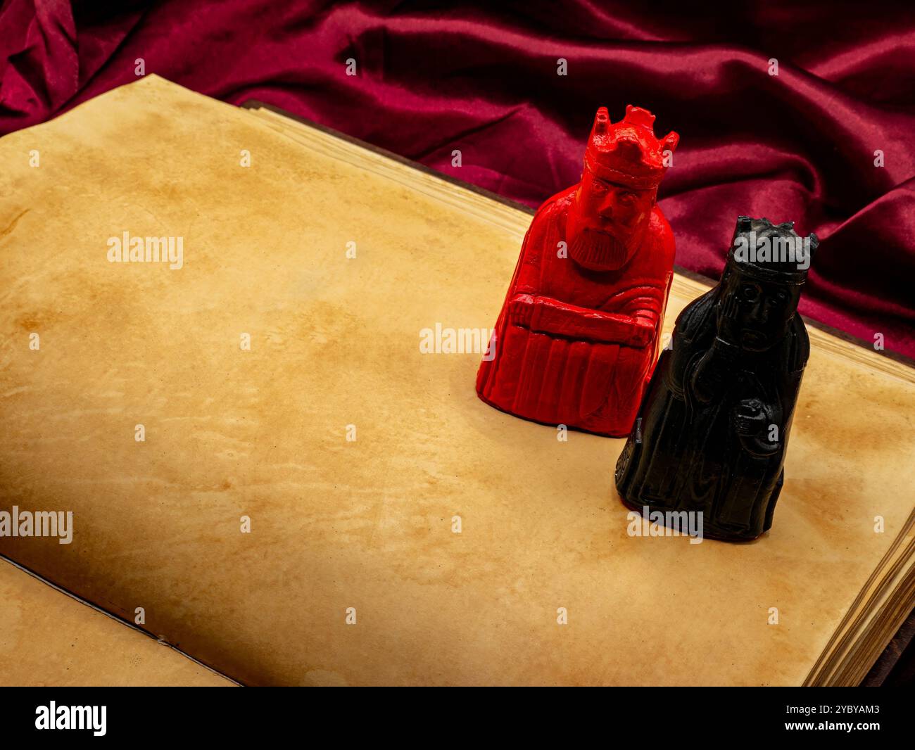 yellowed medieval ancient blank book open on a table with small statues ...