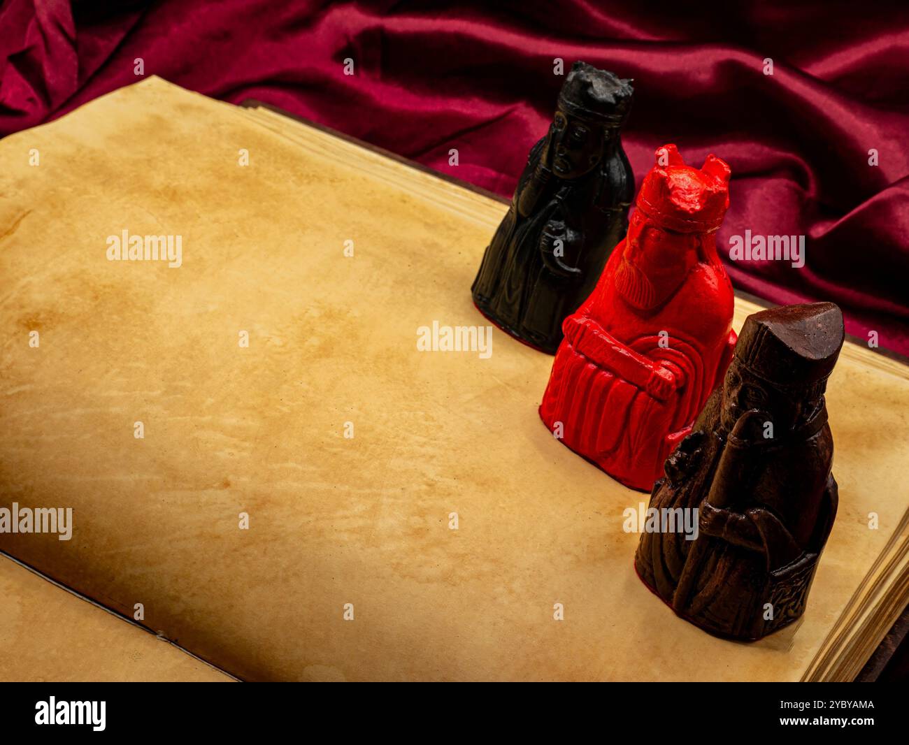 yellowed medieval ancient blank book open on a table with small statues ...