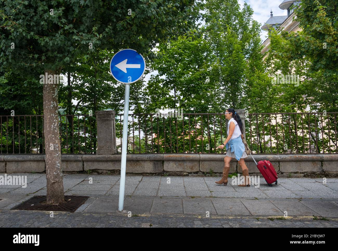 a beautiful adult woman walks with her red trolley suitcase in front of ...