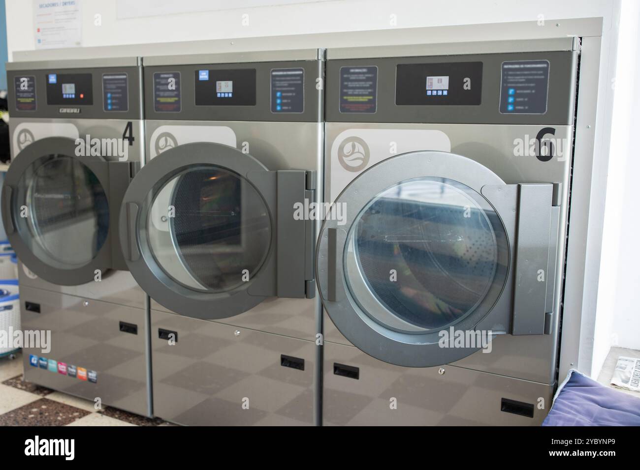 Modern coin-operated laundry machines in a bright, clean laundromat ...