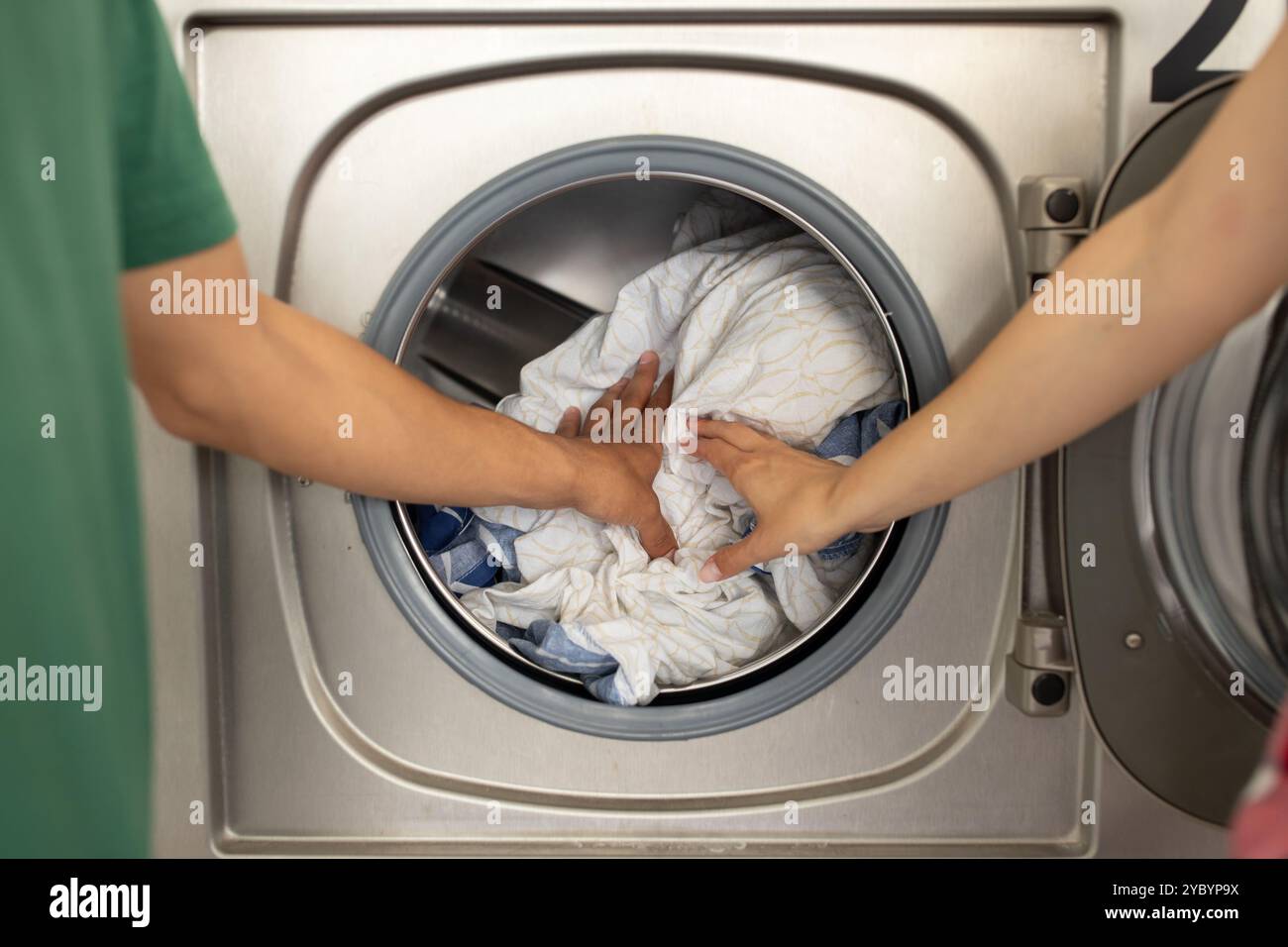 Couple doing laundry together in a modern washing machine at home Stock ...