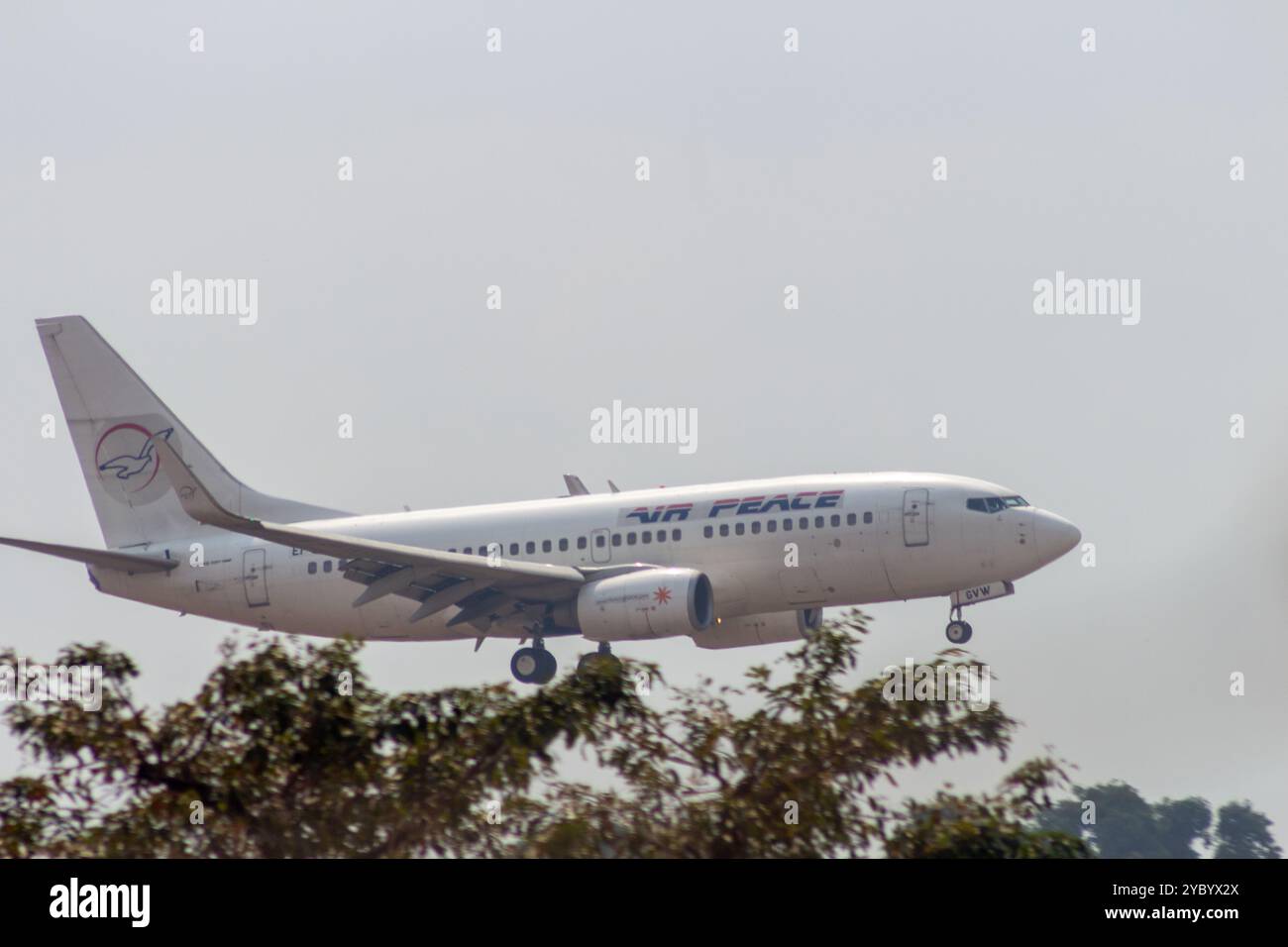 A small Air Peace aircraft flying low over trees as it descends into ...