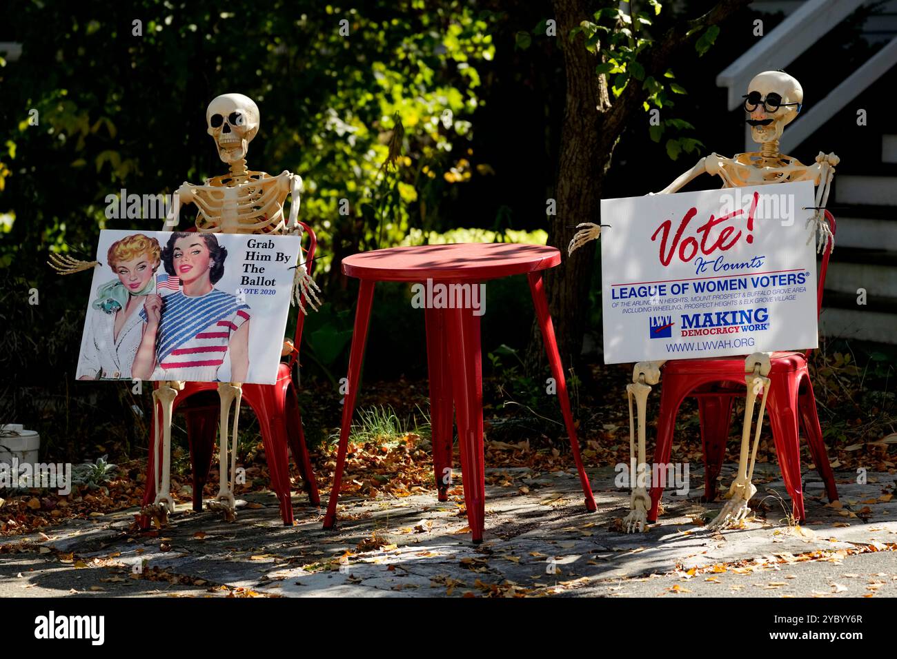 A Halloween skeleton sits with an election campaign poster outside of a ...