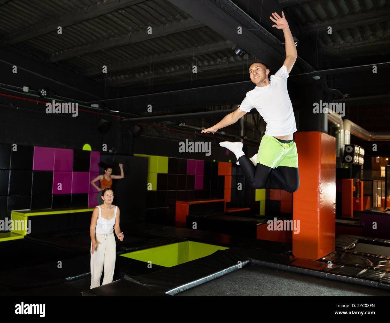 Emotional man jumping vertical and flying in trampoline sport center ...