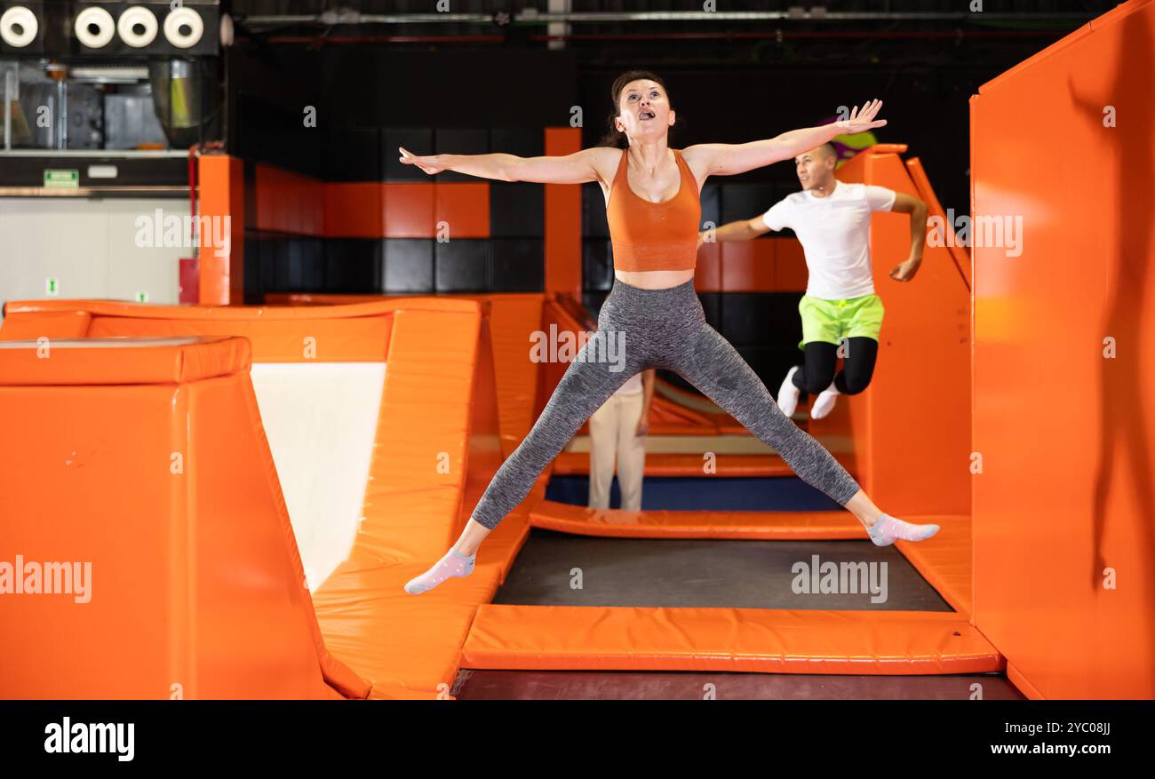 Excited woman enjoying jumping at well-equipped indoor trampoline arena ...