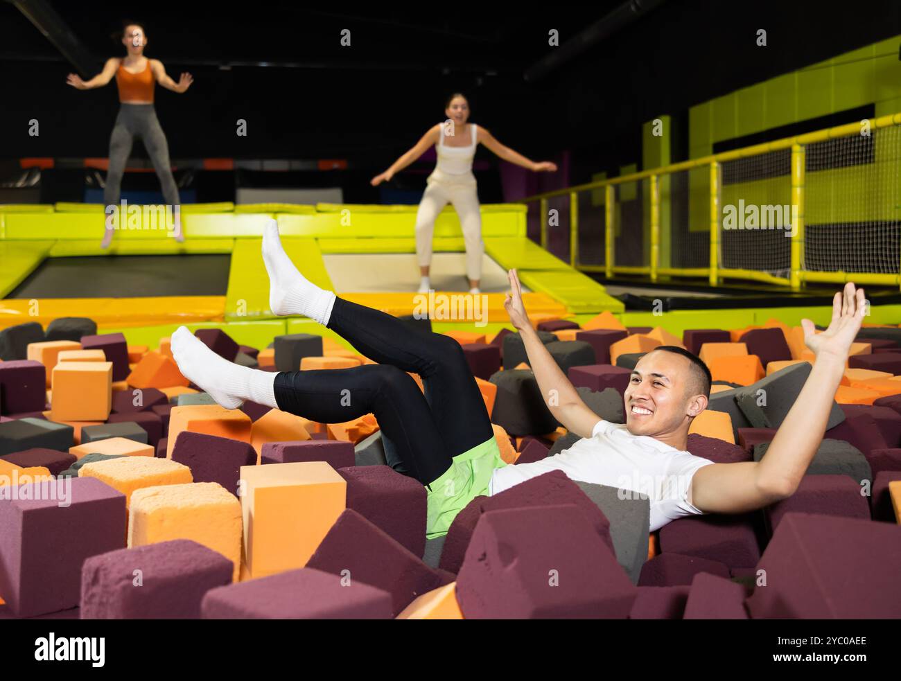 Joyful guy jumping into foam pit at indoor trampoline arena Stock Photo ...