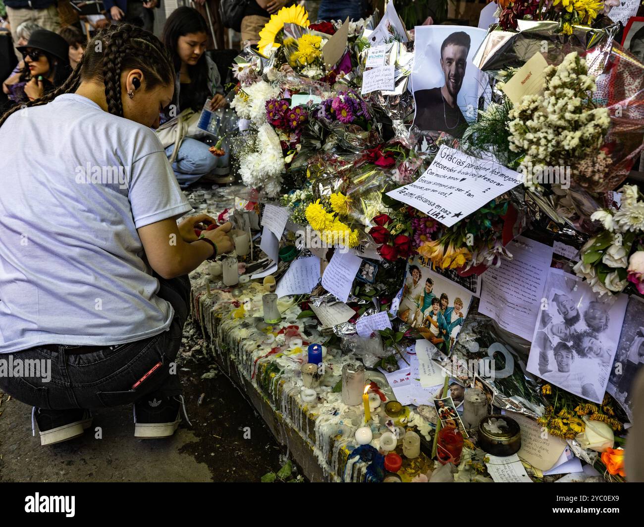 A Liam Payne fan lights a candle at the improvised altar at the door of ...