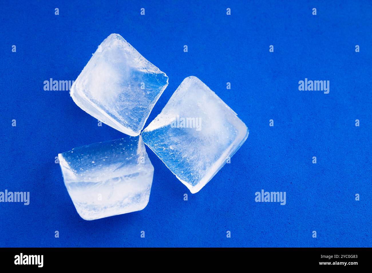Three ice cubes on blue background Stock Photo - Alamy
