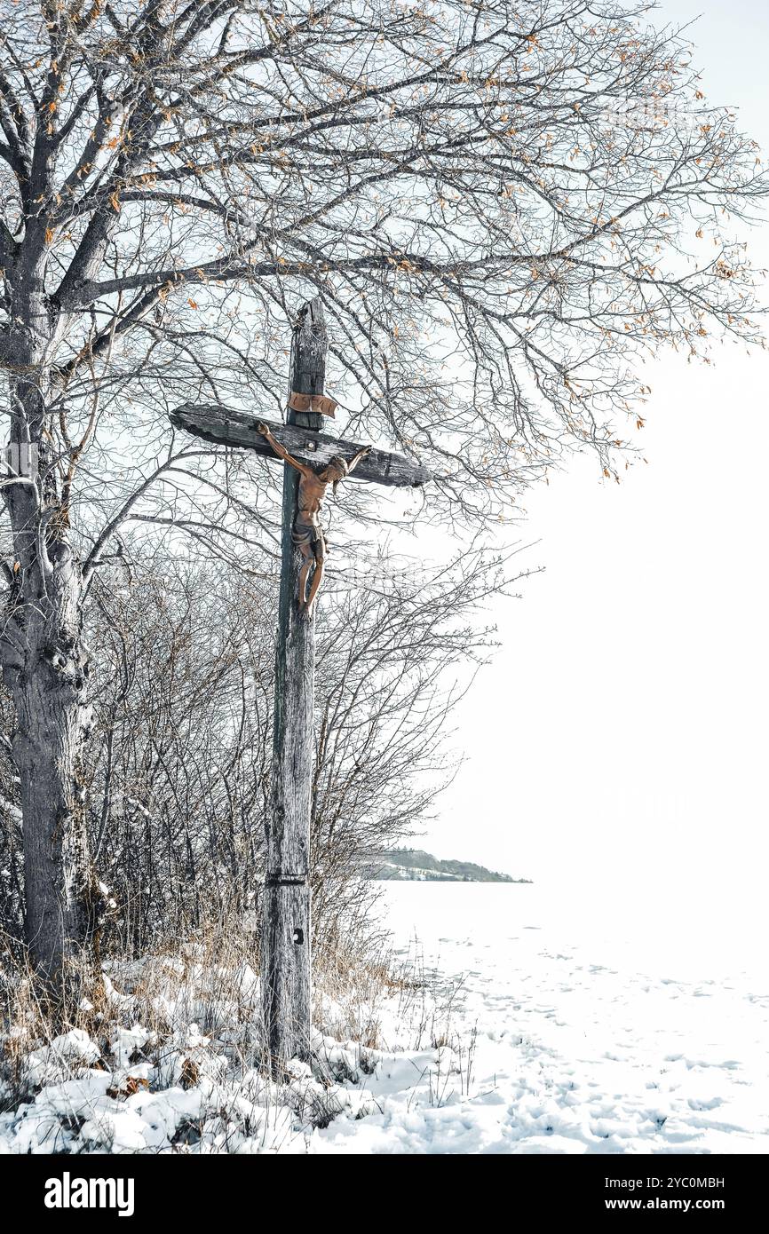 Wooden cross with statue of jesus christ in grove on white snowy ...
