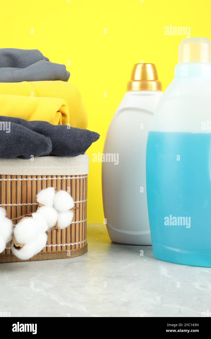 Laundry detergent in bottles, cotton flowers and clothes on grey marble ...