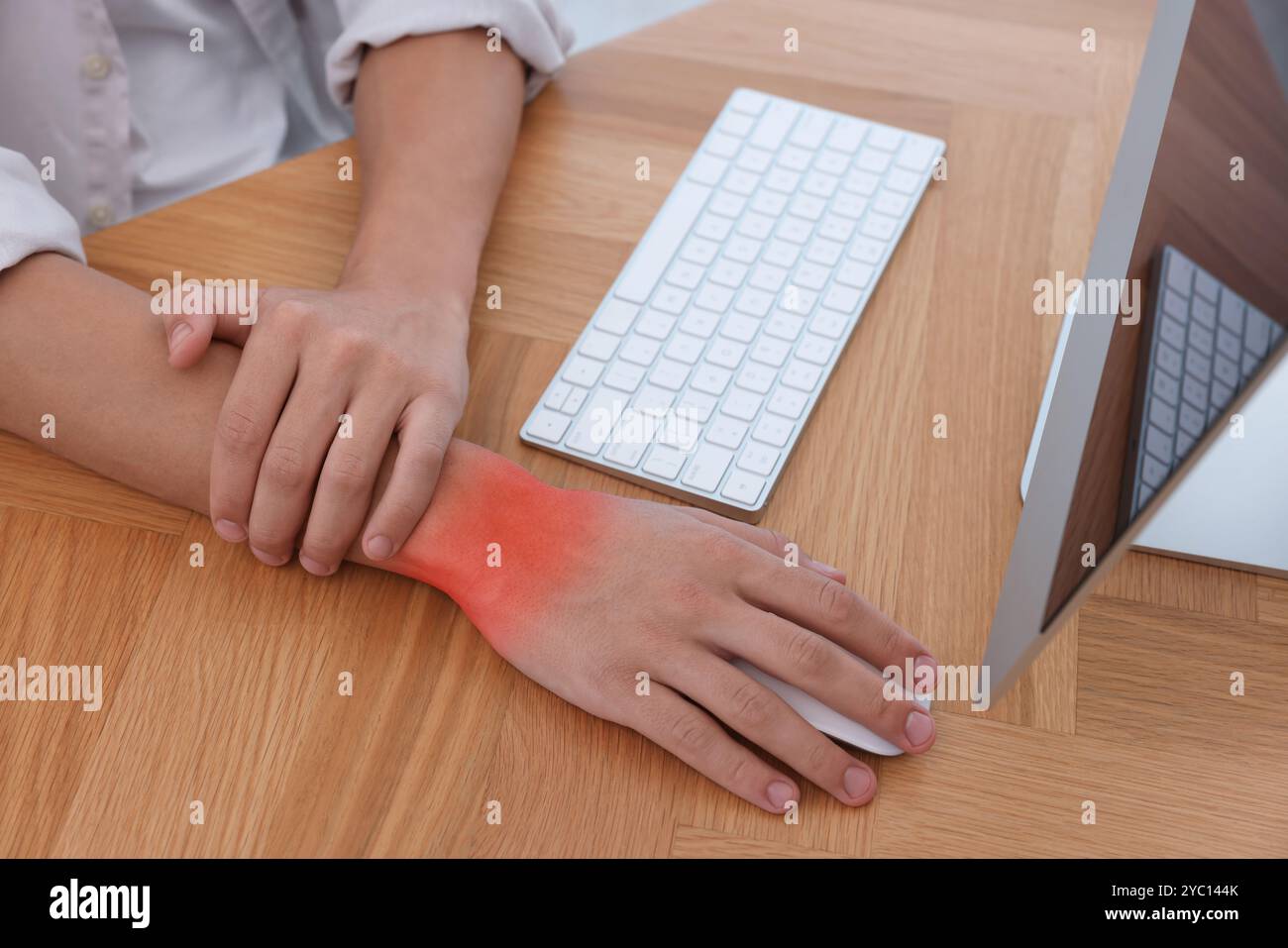 Man suffering from pain in wrist while using computer mouse at wooden ...