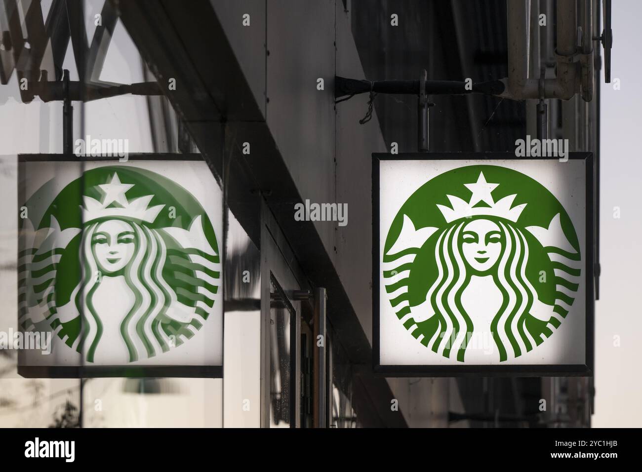 Illuminated Starbucks logo reflected in window pane, city centre ...