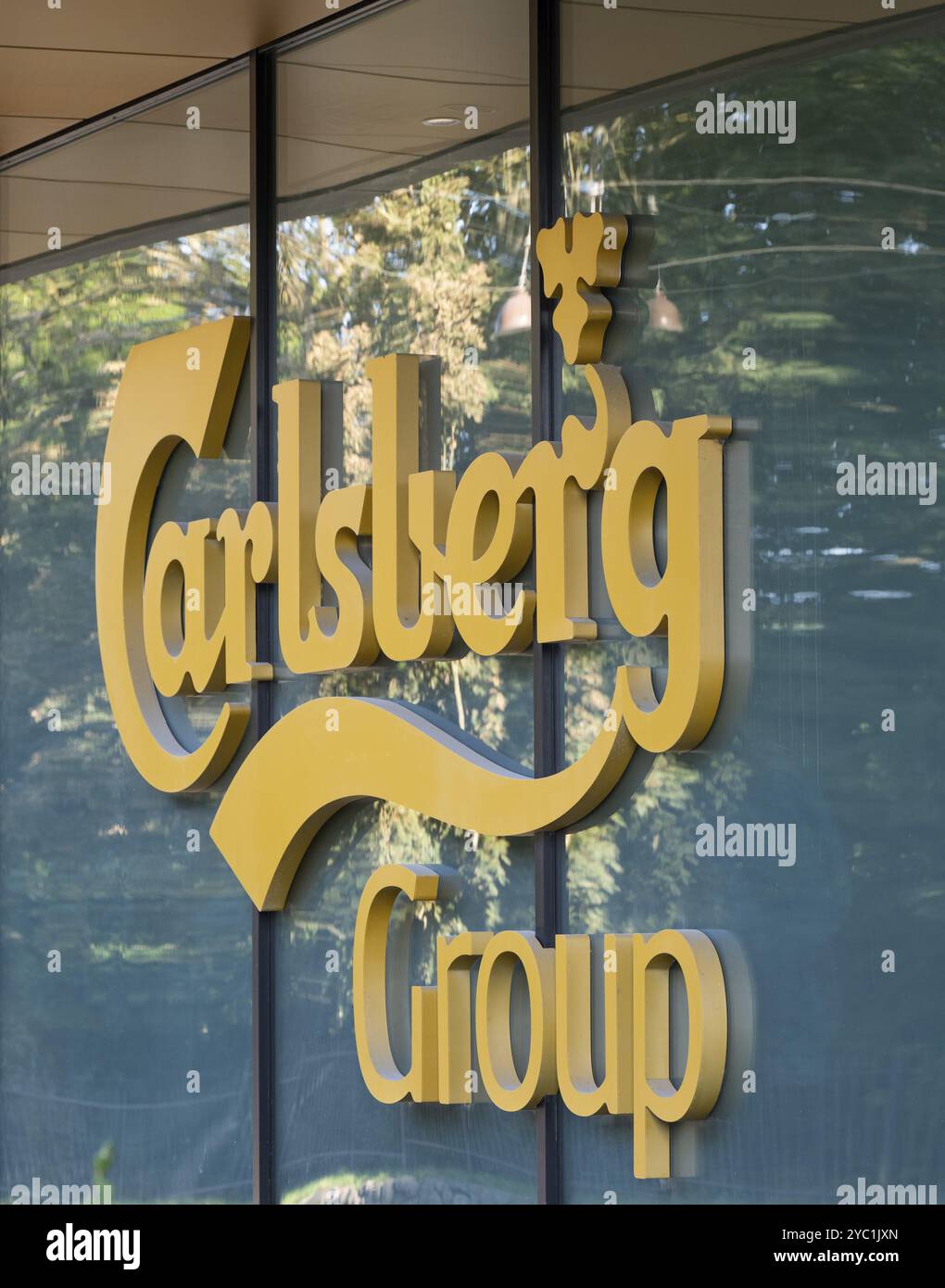 Golden yellow Carlsberg Group logo on a reflective glass facade ...