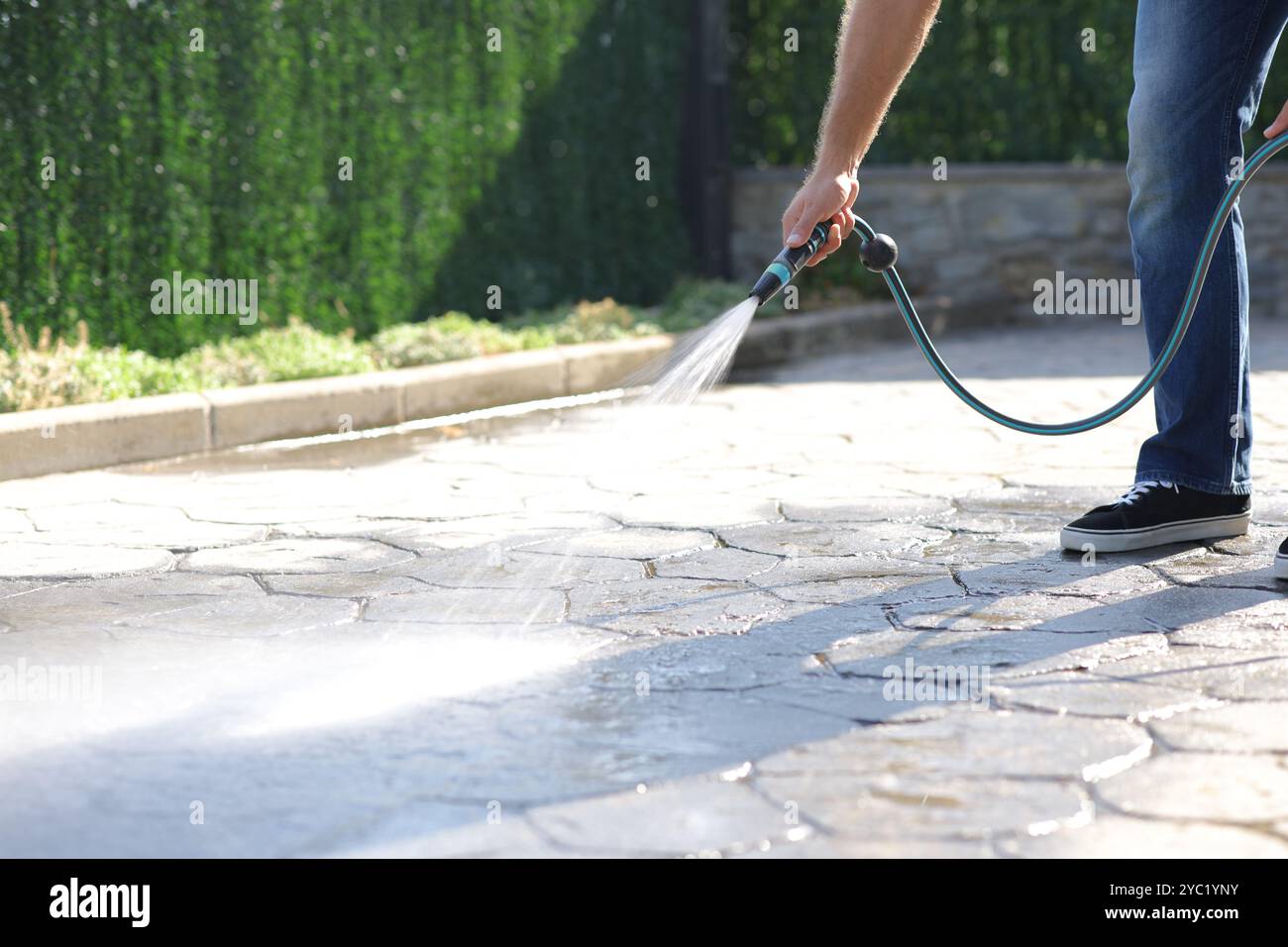 Close up of a man cleaning garden floor with water using hosepipe Stock ...
