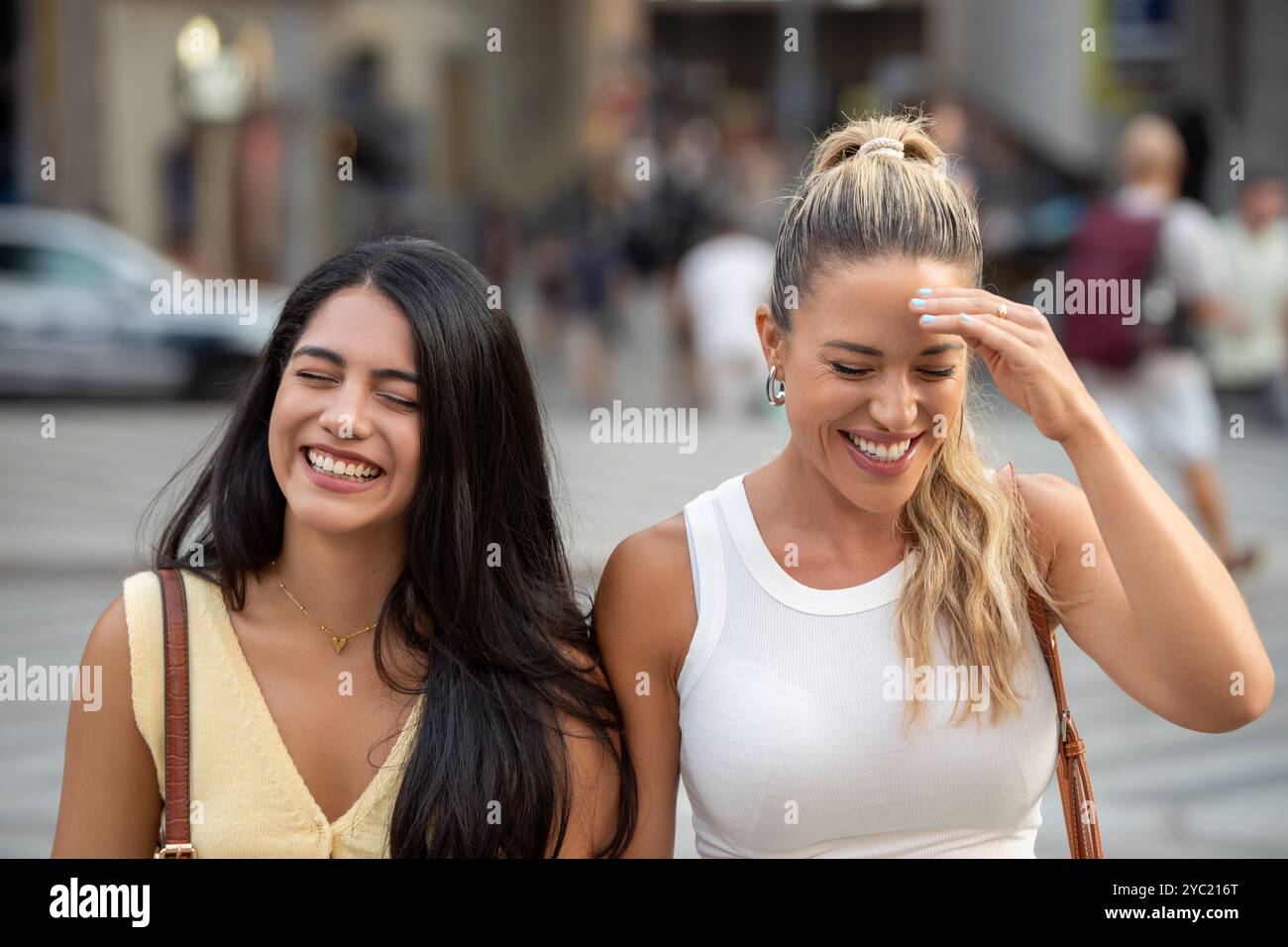 Two friends are having fun together while walking on a city street ...