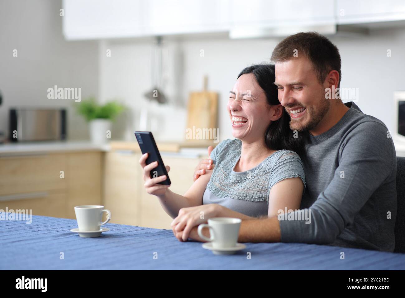 Funny interracial couple laughing hilariously checking phone in the ...