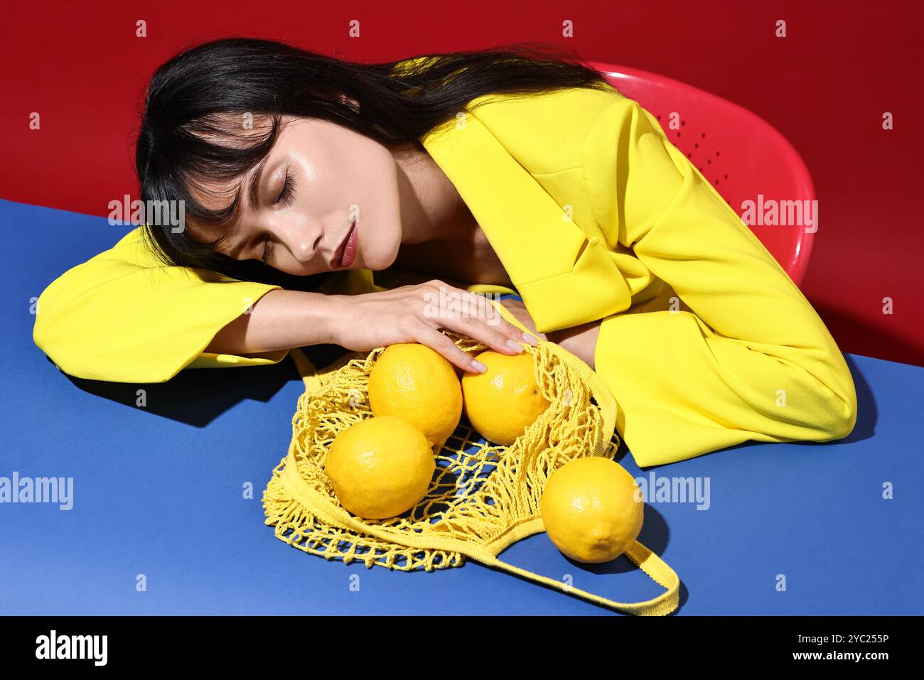 Woman with net bag and lemons at blue table on red background Stock ...