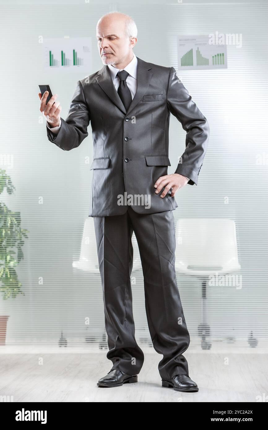 Mature businessman in a sharp suit looks worried while checking his ...