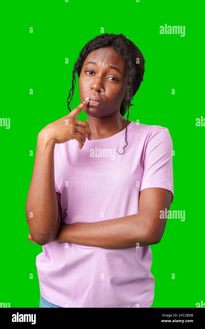 Thoughtful woman pondering in front of a bright green background during ...