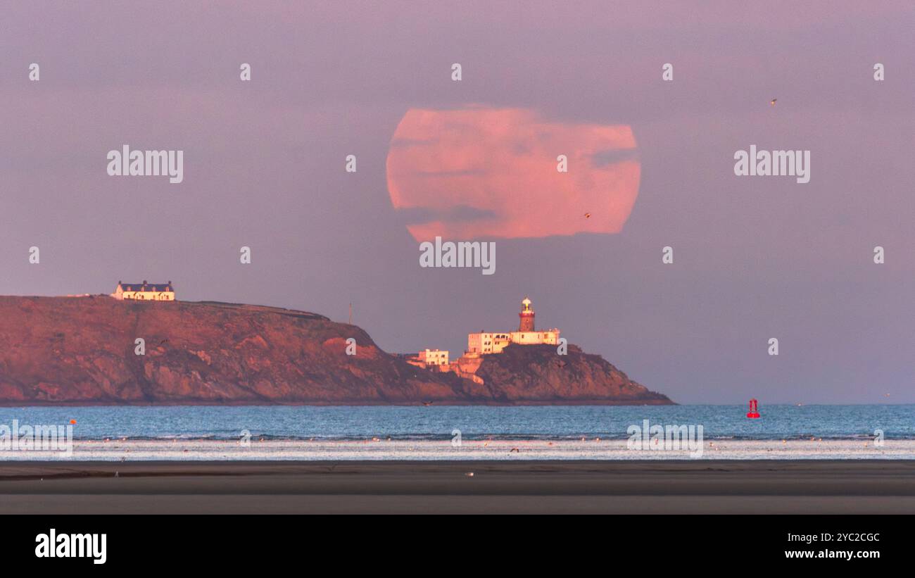 Faint full moon rising over the Baily Lighthouse lined up from ...