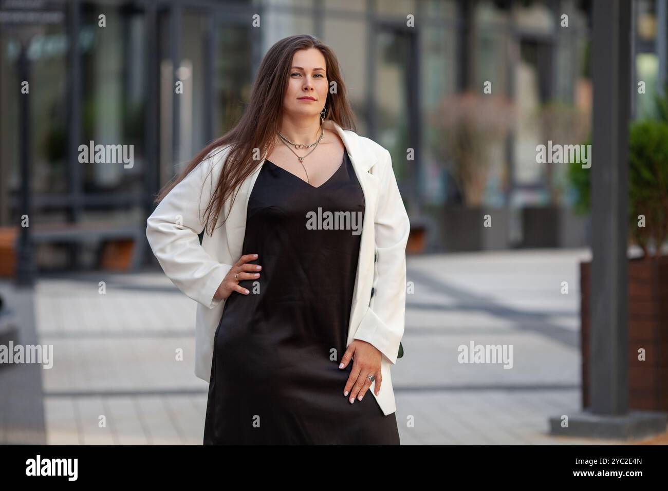 Plus size stylish woman stands outdoors in urban setting at city ...