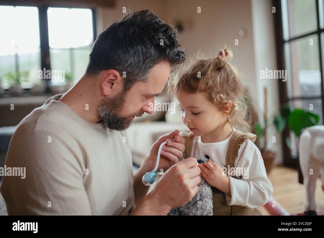 Father helping daughter with stuffy nose, using nasal suction bulb to ...