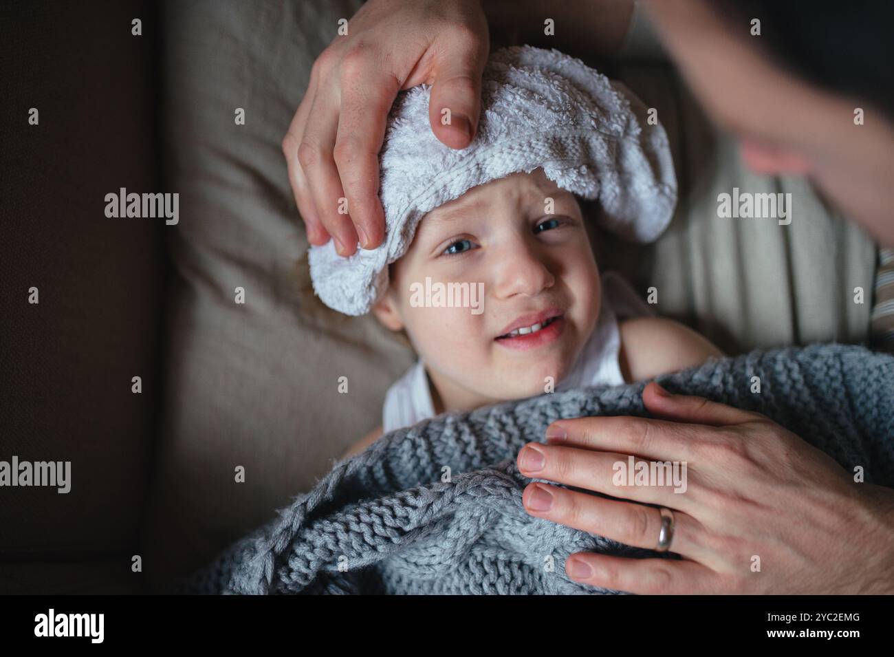 Father taking care of sick son with fever and cold, holdig cold cloth ...