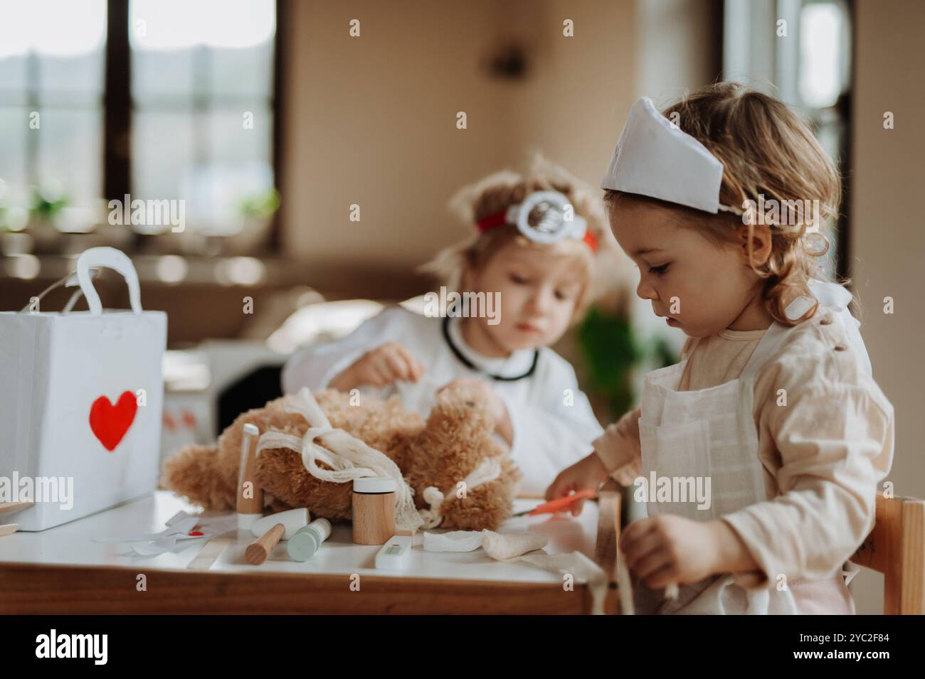 Siblings in doctor uniforms are playing hospital, taking care of sick ...