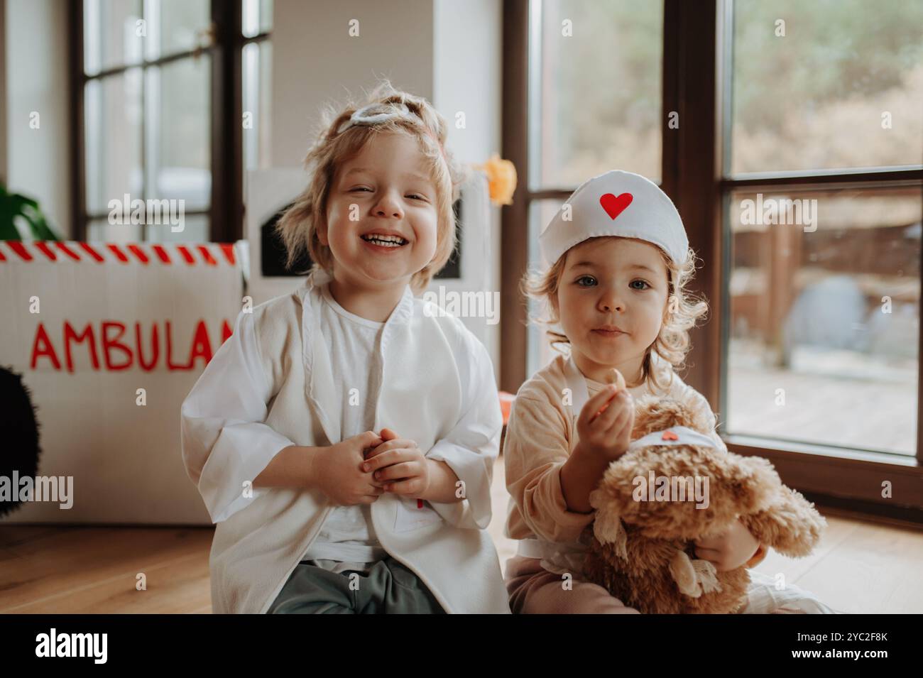 Siblings in doctor uniforms are playing hospital, taking care of sick ...